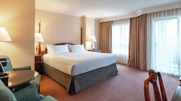 Quarto de hotel com uma cama, duas mesas de cabeceira com luminárias, uma cadeira e uma mesinha.