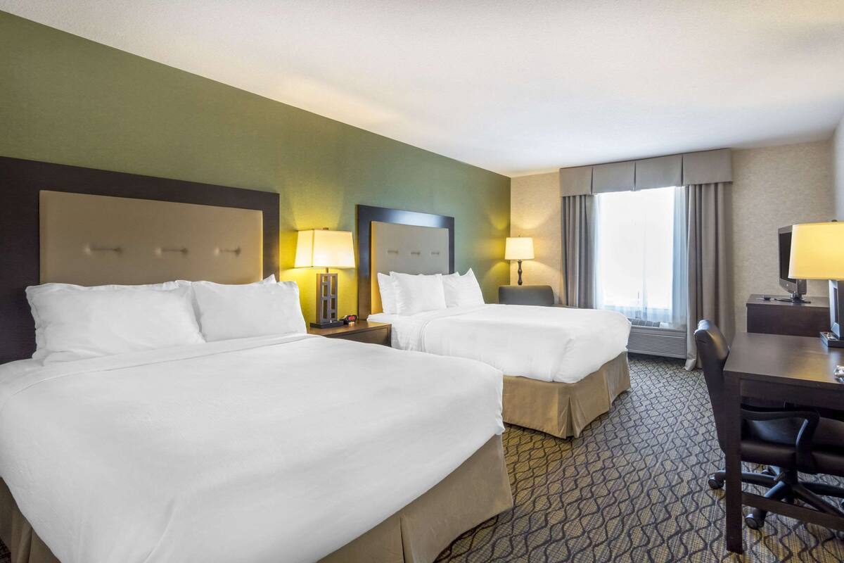 Quarto de hotel com duas camas, uma escrivaninha e uma cadeira.