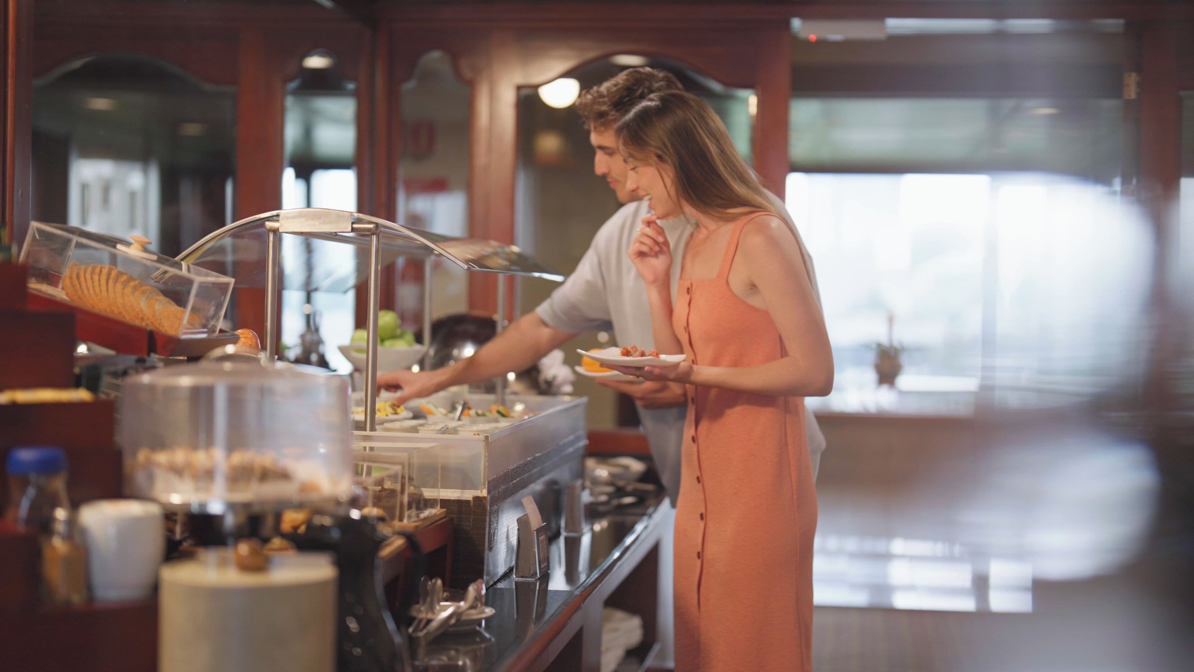 Uma mesa de buffet com diversos tipos de comida e um dispensador de bebidas.