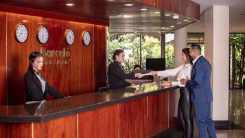 Uma receção com acabamento em madeira, relógios e um sinal da Barceló Hotels & Resorts.