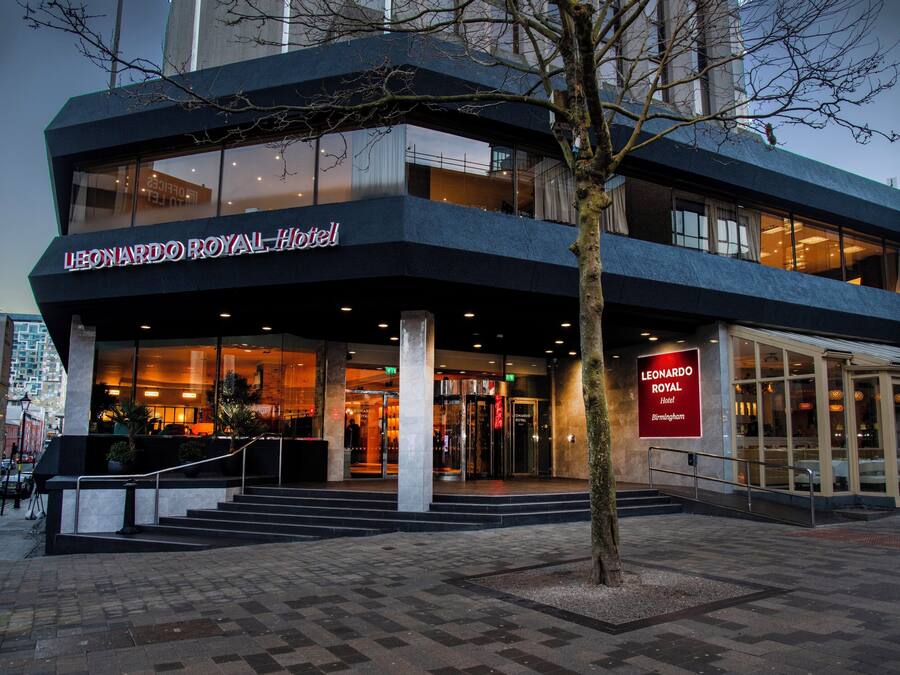 Exterior do Hotel Leonardo Royal com design moderno, destacando uma entrada imponente, uma escadaria que leva ao saguão e uma grande fachada de vidro.