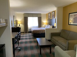 Quarto de hotel com uma cama, uma mesa, uma cadeira, um sofá e uma pequena mesa.