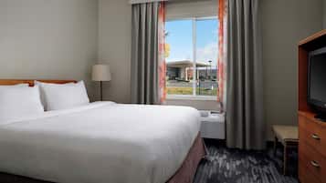Quarto de hotel com uma cama grande, televisão, escrivaninha e janela com cortinas.