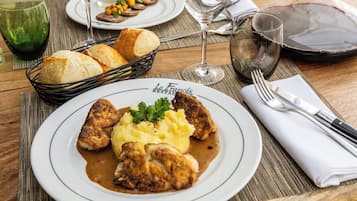 Uma mesa de jantar com um prato de comida, uma cesta de pão e copos de vinho.