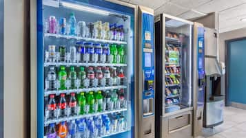 Uma fileira de máquinas de venda automática com diversas opções de bebidas.
