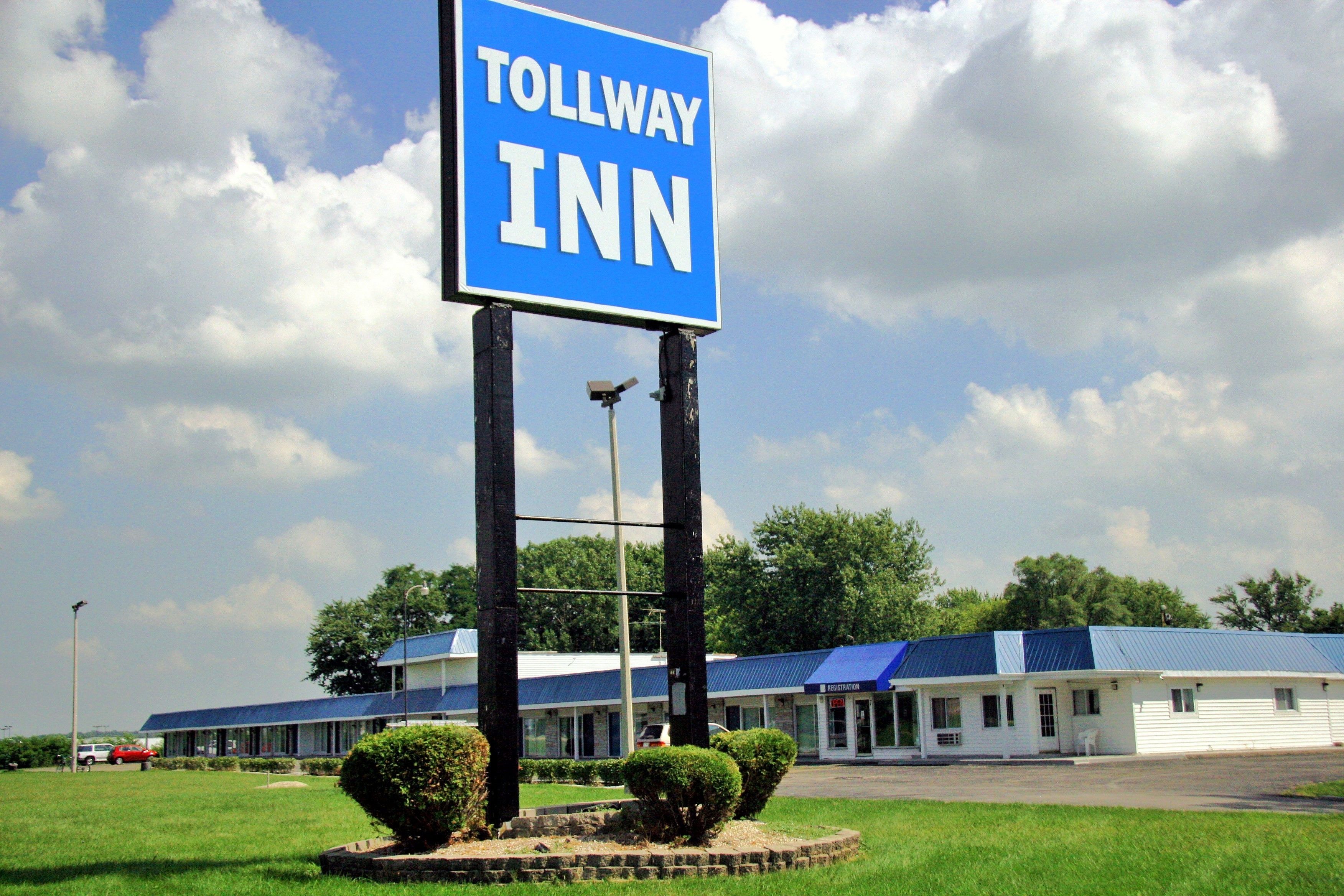 Um sinal azul para um Tollway Inn, com um prédio de motel ao fundo.