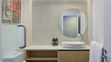 Uma casa de banho moderna com um espelho redondo, uma pia branca e um porta-toalhas.