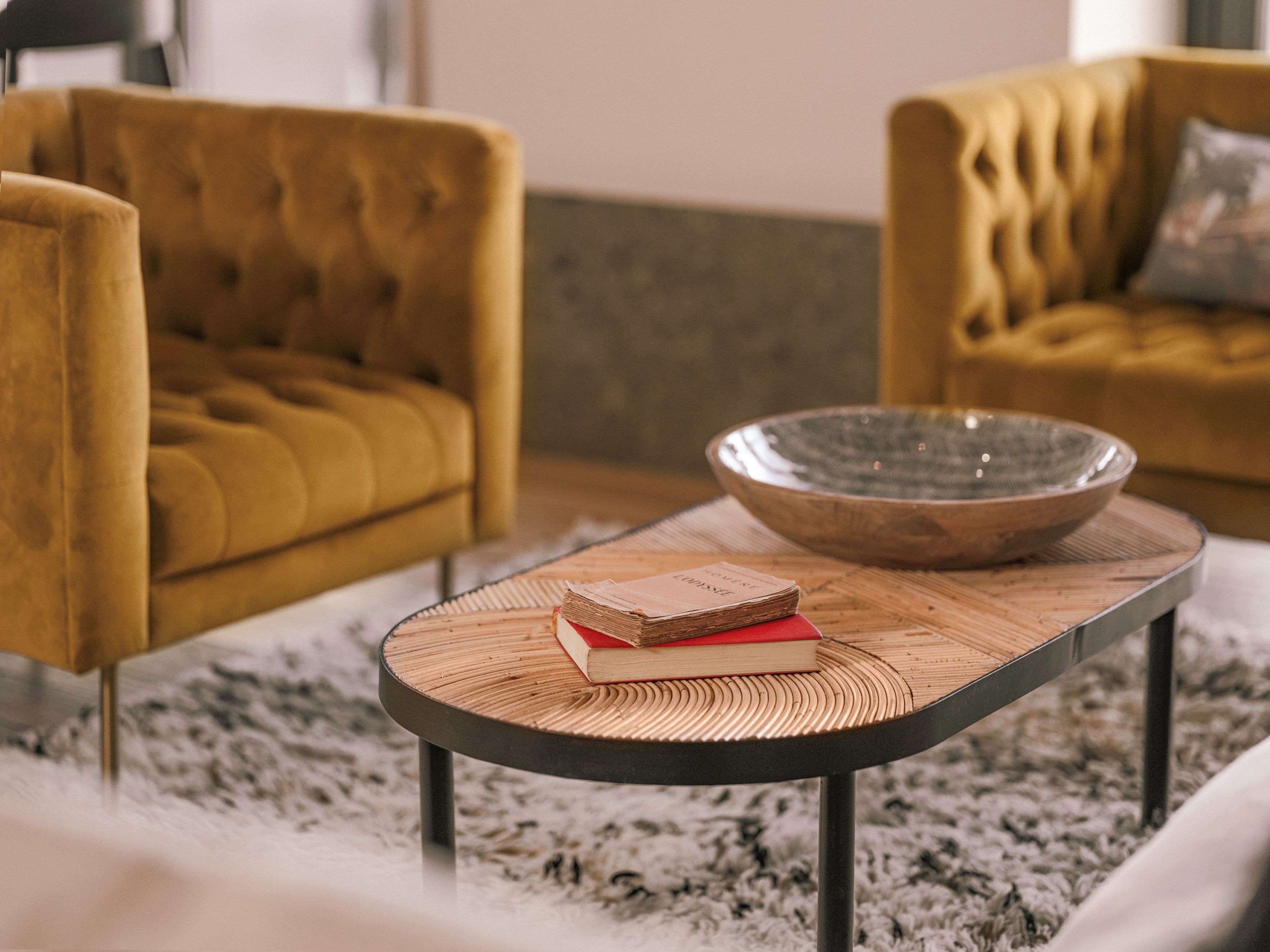 Uma sala de estar moderna com uma mesa de centro redonda, dois sofás e uma tigela sobre a mesa.