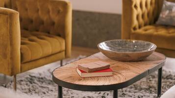 Uma sala de estar moderna com uma mesa de centro redonda, dois sofás e uma tigela sobre a mesa.