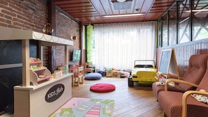 Espaço infantil com lousa, brinquedos e um tapete colorido.