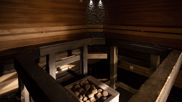 Uma sauna com bancos de madeira e uma parede de pedra ao fundo.