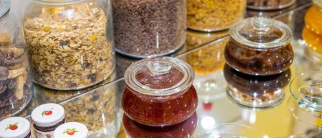 Diversos alimentos em recipientes de vidro, incluindo potes de granola, creme de chocolate e outros lanches.