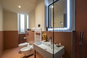 Uma casa de banho moderna com uma pia branca, um espelho grande e uma sanita.