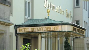 Um hotel com estilo arquitetônico clássico, com uma placa destacada exibindo o nome 'Detmolder Hof' e um emblema dourado decorativo no telhado.