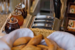 Um buffet de café da manhã com potes de geleia, uma torradeira e uma cesta de pão.