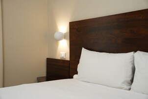 Cama bem arrumada com lençóis brancos em quarto de hotel.