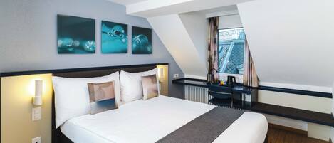 Quarto de hotel moderno com uma cama grande, uma escrivaninha e vista para um edifício através da janela.