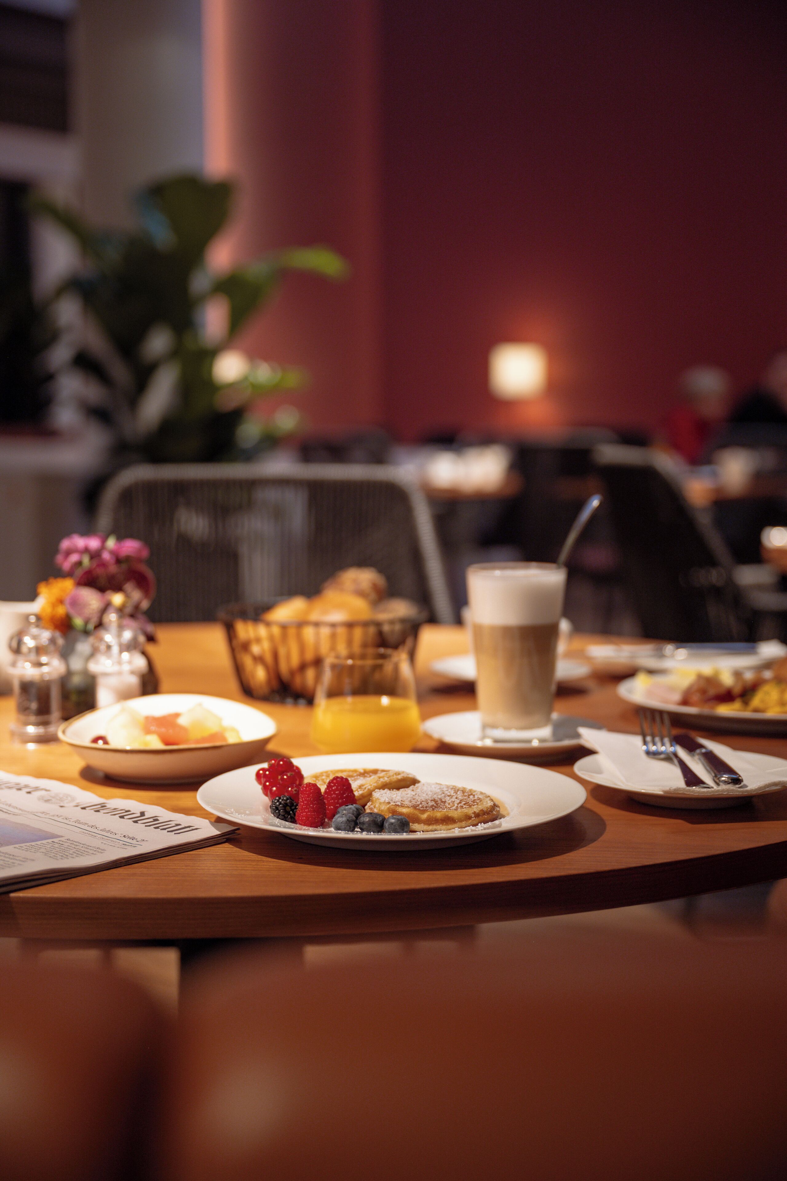 Uma mesa de café da manhã com pratos de comida, um copo de suco de laranja e uma xícara de café.