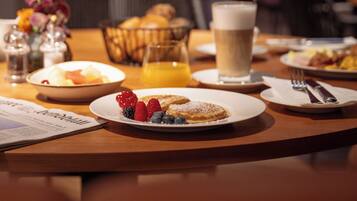 Uma mesa de café da manhã com pratos de comida, um copo de suco de laranja e uma xícara de café.