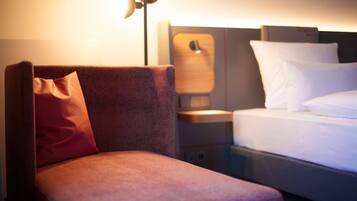 Quarto de hotel com uma cama, mesa de cabeceira e uma cadeira.