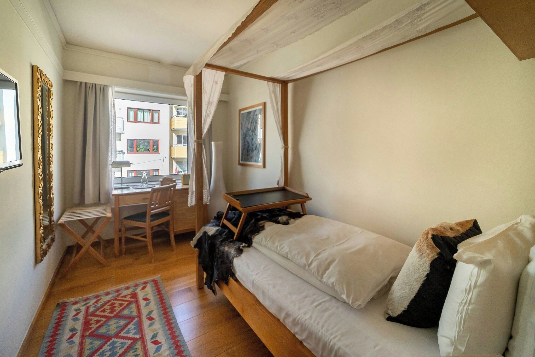 Um quarto com uma cama, uma escrivaninha e uma cadeira.