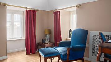 Um quarto com duas poltronas azuis, uma mesa de madeira com abajur e um radiador.
