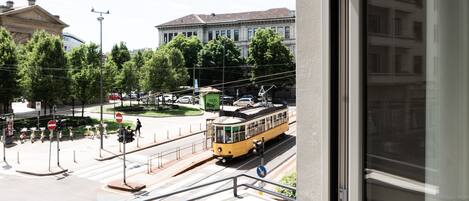 Um elétrico nos trilhos, uma faixa de pedestres e edifícios ao fundo.
