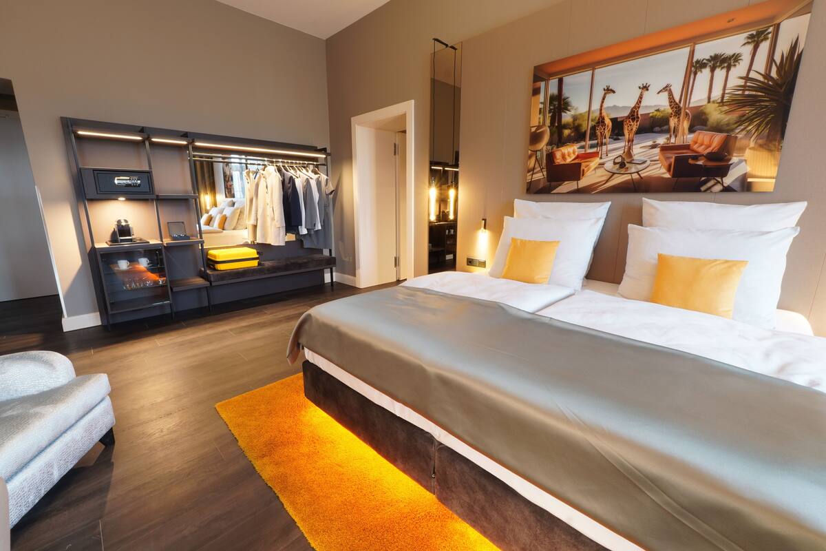 Quarto de hotel moderno com uma cama grande, um closet espaçoso e uma pintura de girafas.