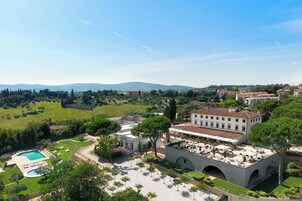 Uma grande villa com piscina, área de estar ao ar livre e vista para o campo circundante.