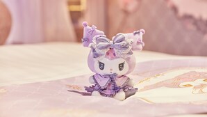 Um brinquedo macio sobre a cama, com um edredom estampado.