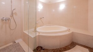 Um banheiro moderno com chuveiro em cabine de vidro, banheira separada e piso de mármore.