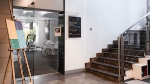 Uma sala de conferência com divisória de vidro, um cavalete de madeira com um gráfico, uma escada e uma placa indicando salas de conferência.