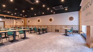 Uma sala de conferências com mesas, cadeiras, um painel de madeira e teto com iluminação embutida.