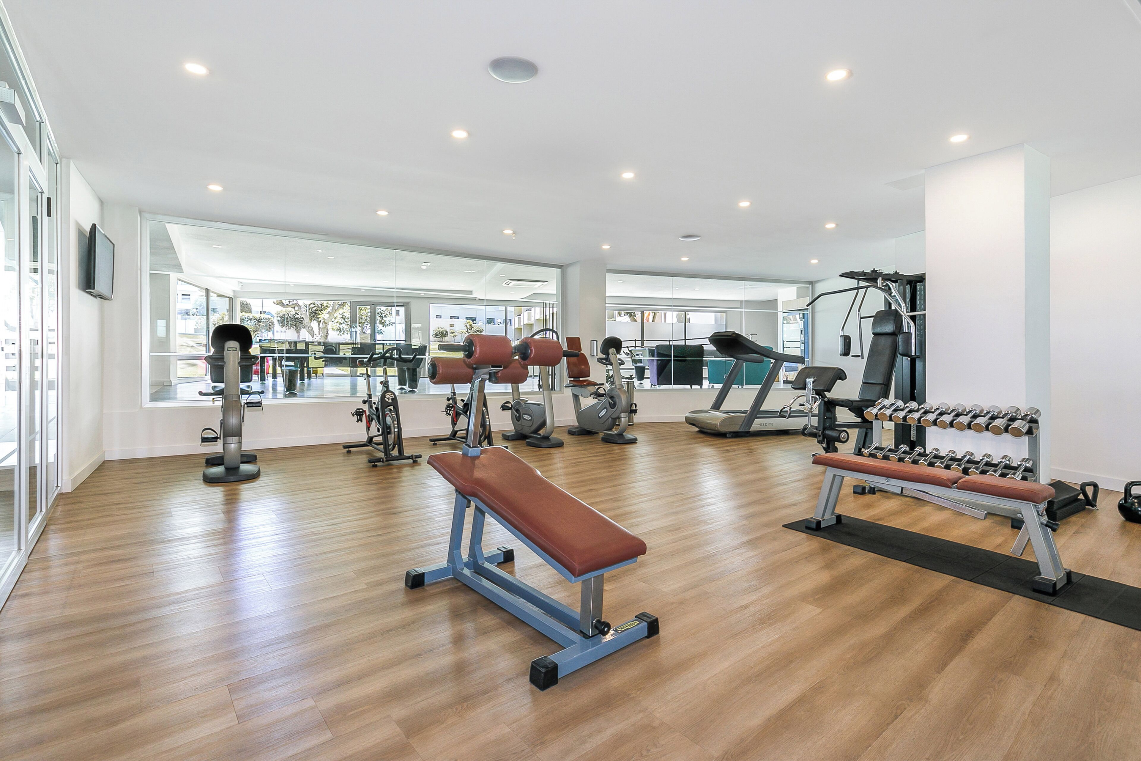 Uma academia moderna com diversos equipamentos de exercício, incluindo um banco, halteres e aparelhos de cardio.
