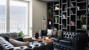 Uma sala de estar moderna com um sofá de couro, uma estante e uma janela com vista.