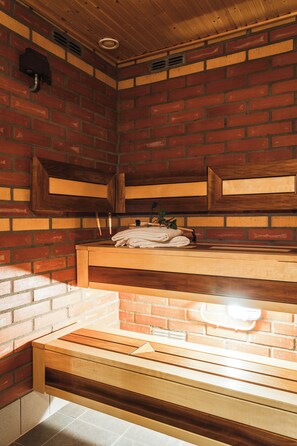 Uma sauna com bancos de madeira, parede de tijolos e um porta-toalhas.