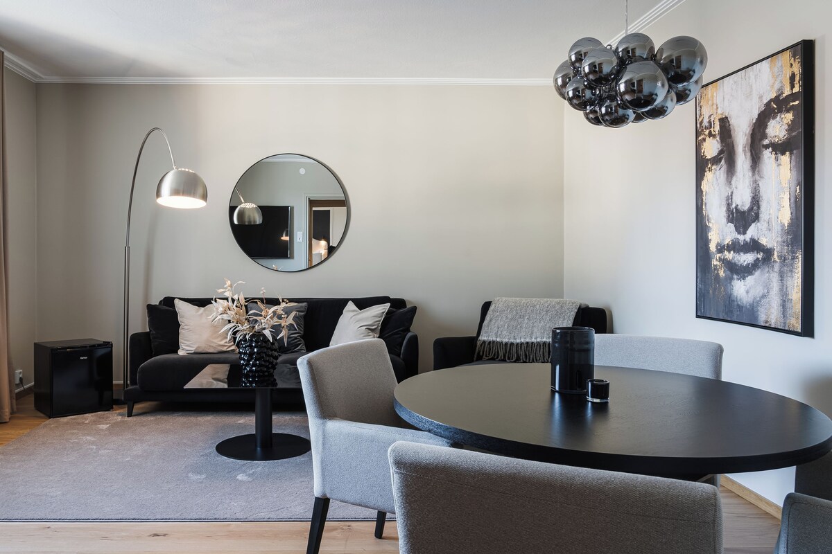 Uma sala de estar moderna com uma mesa de jantar redonda, um sofá, um abajur e um espelho grande na parede.