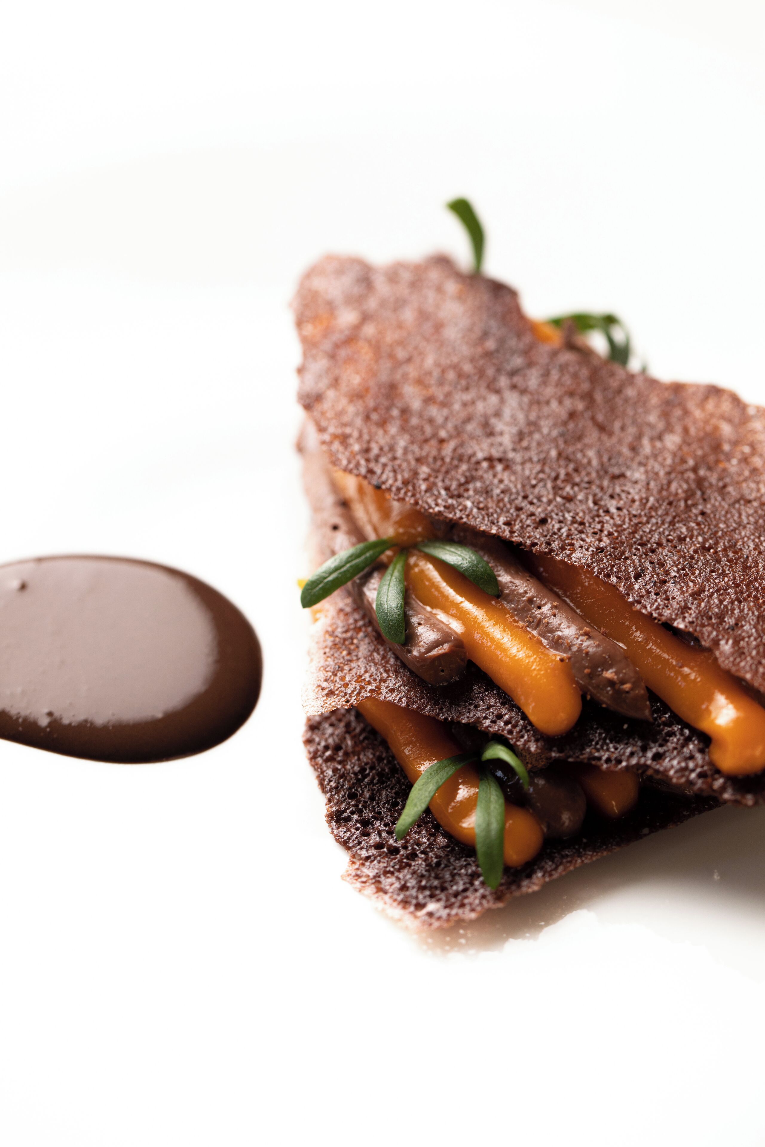 Uma sobremesa com chocolate e caramelo, decorada com folhas verdes.