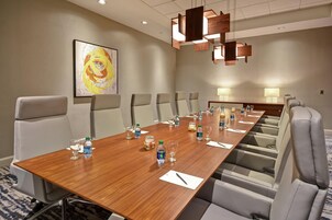 Uma sala de conferência com uma mesa comprida, várias cadeiras, garrafas de água e copos.