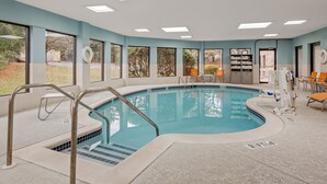 Piscina com água azul cristalina, rodeada por um deck ladrilhado e uma escada de metal.