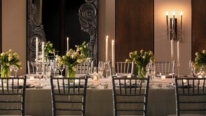 Mesa de jantar formal posta com velas, copos e arranjos florais.
