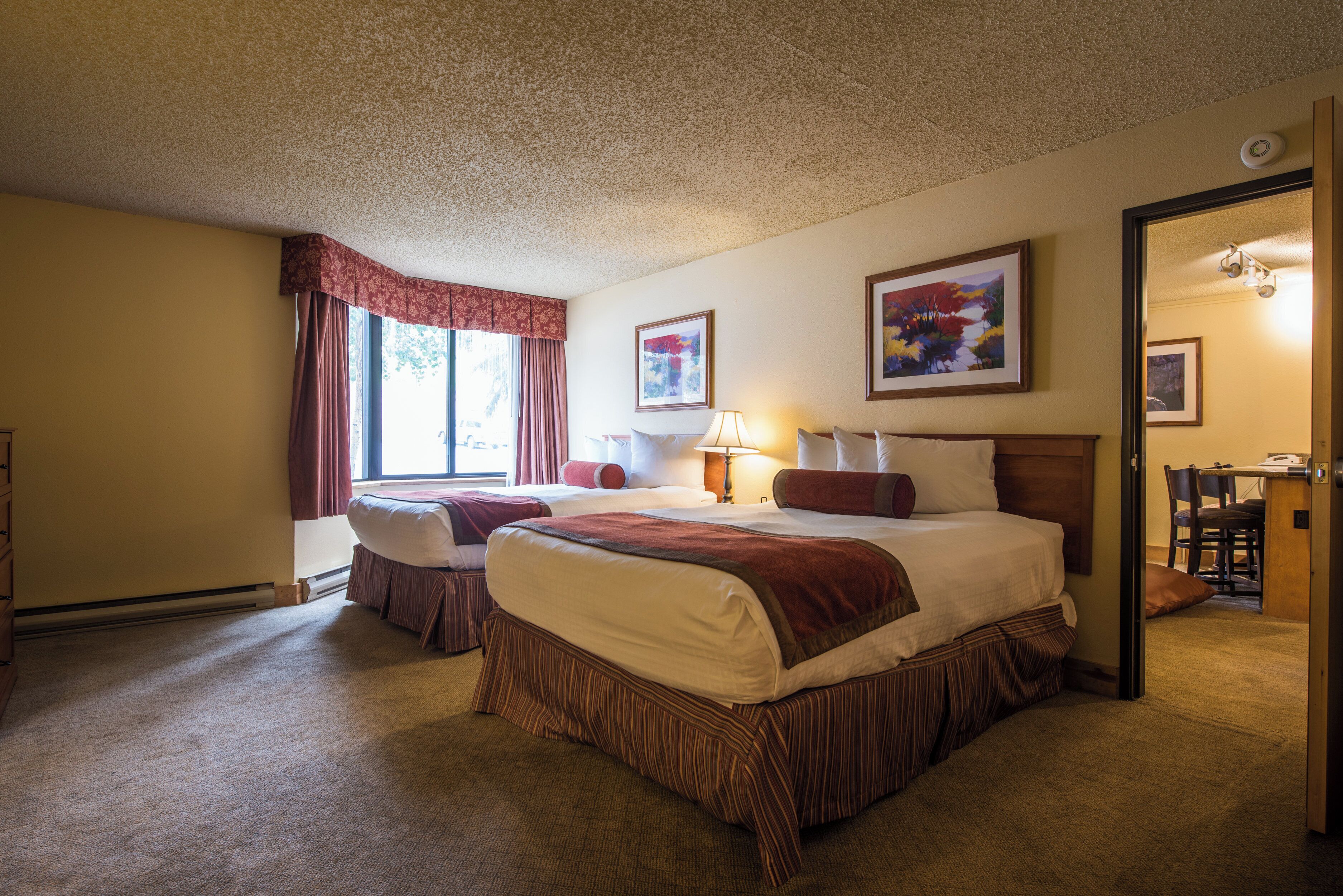 Quarto de hotel com duas camas, uma escrivaninha e uma cadeira.