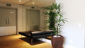 Quarto moderno com sofá, uma planta grande em vaso e um painel de parede de vidro.