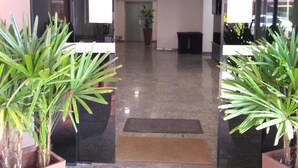 Um lobby moderno com entrada de vidro, plantas em vasos e chão de azulejos.
