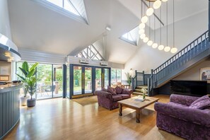 Uma sala de estar espaçosa com pé direito alto, janelas amplas e escada.