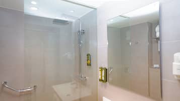 Casa de banho moderna com cabine de duche em vidro, apoio de mão, lavatório e espelho.