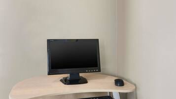 Monitor de computador sobre uma mesa curva, com teclado e rato.