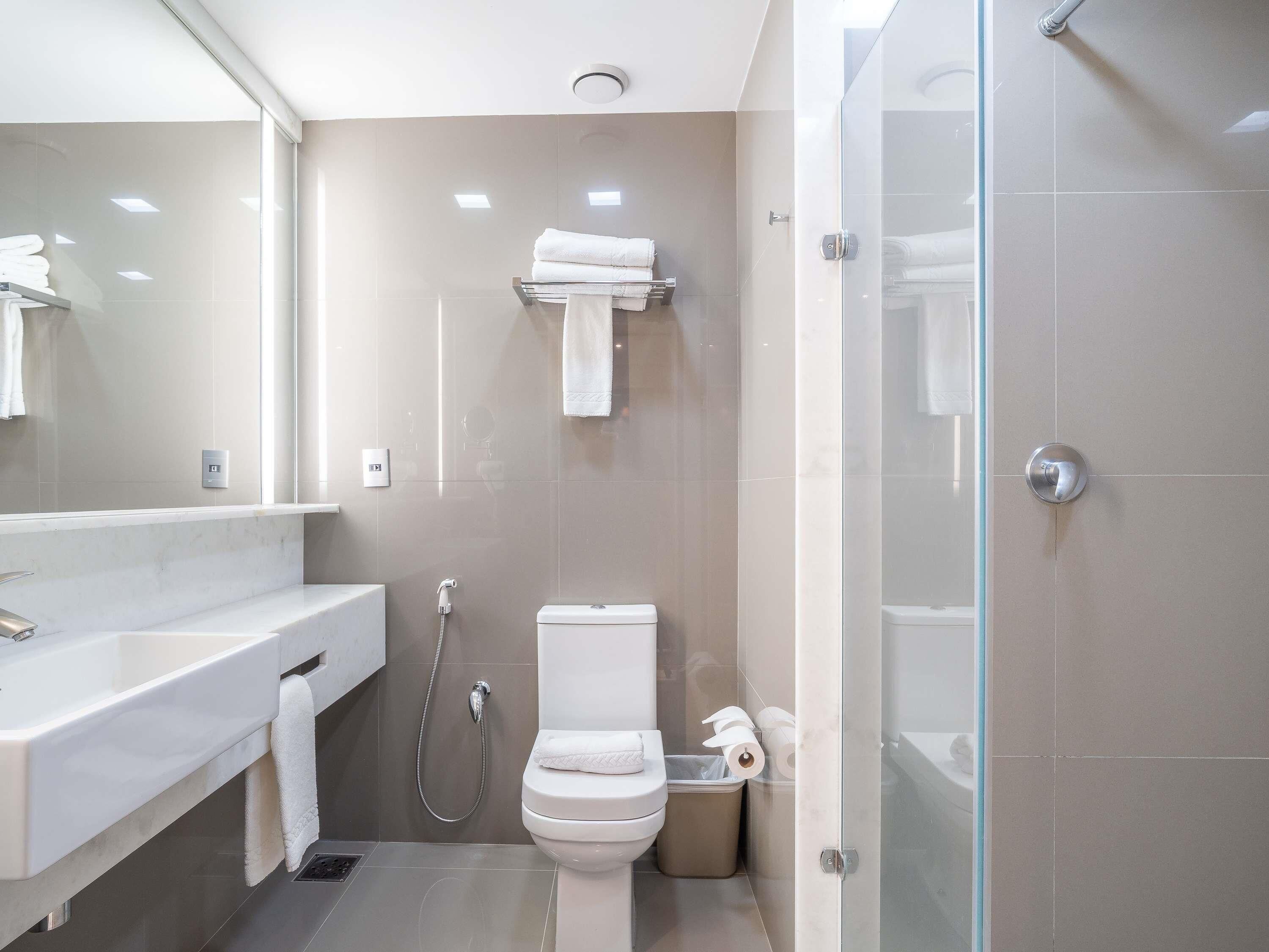 Uma casa de banho moderna com cabine de duche em vidro, sanita e lavatório com espelho.