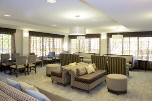 Quarto de hotel com sofá, cadeiras, mesa de jantar e divisória.
