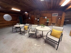 Um quarto rústico de madeira com quatro mesas redondas e cadeiras, cada uma com um assento acolchoado.